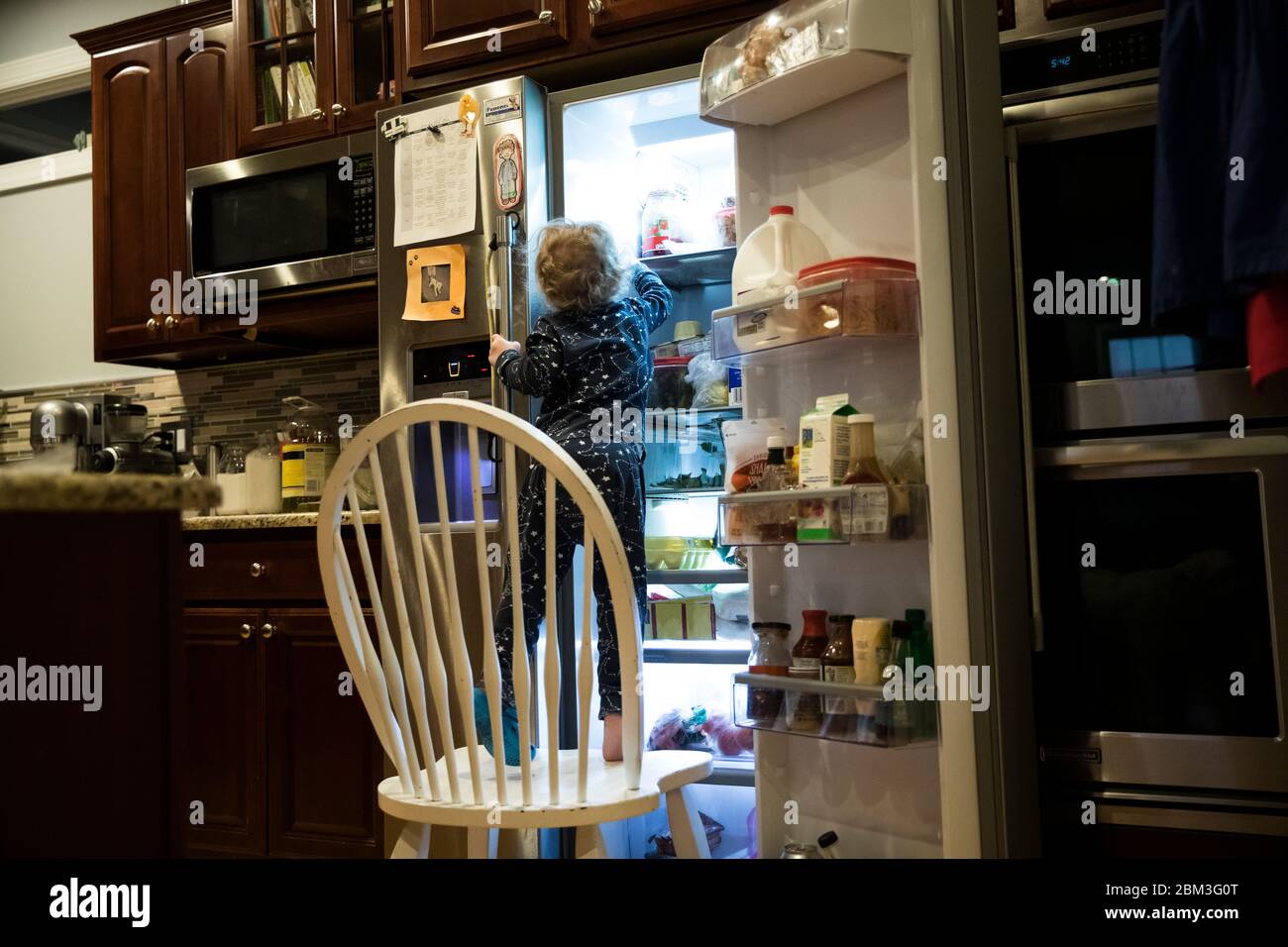 Rear View of Toddler Standing on Chair Reaching Into Open Refrigerator ...