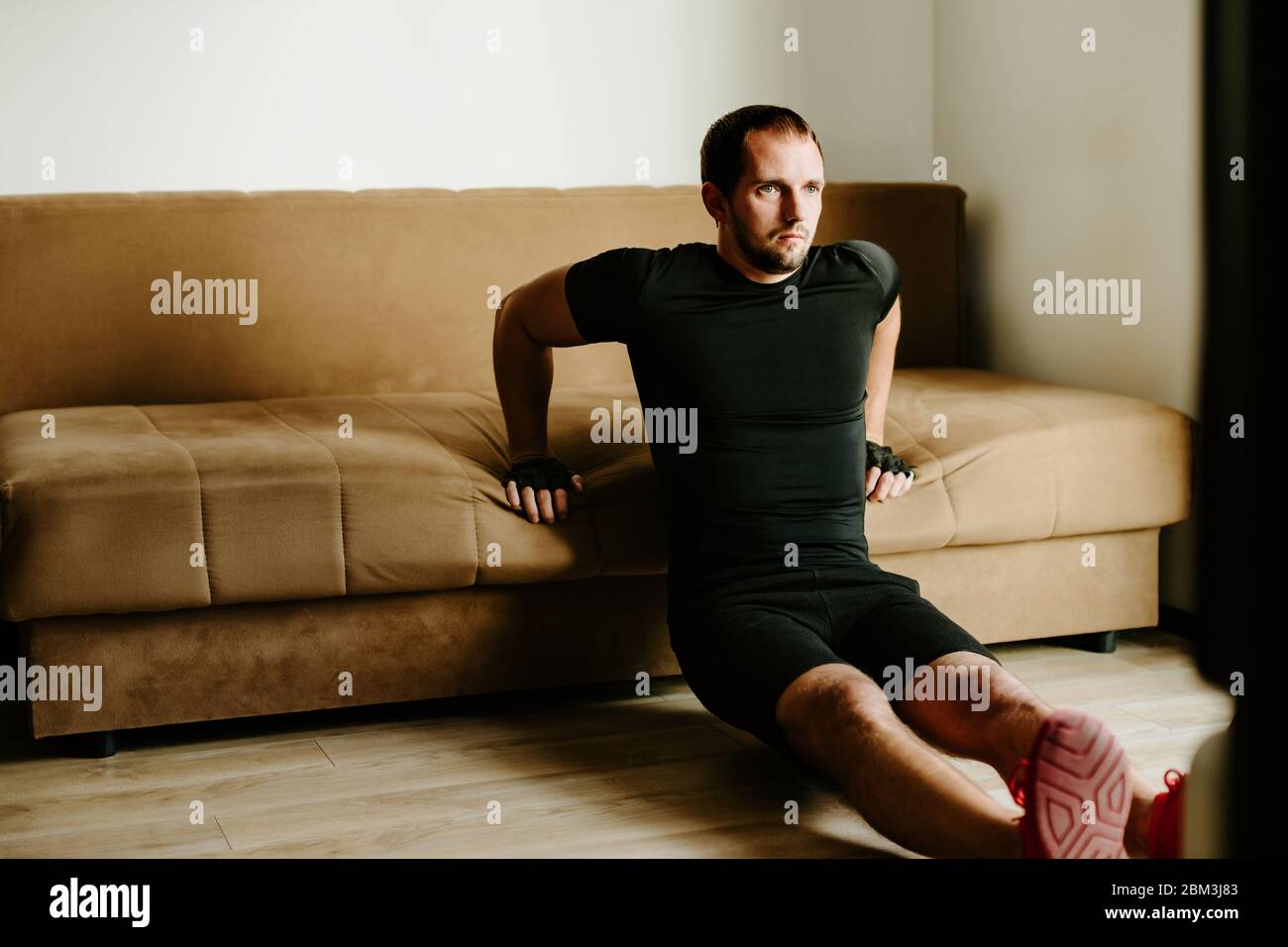 young muscular guy working out at home. Man doing physical excercises ...