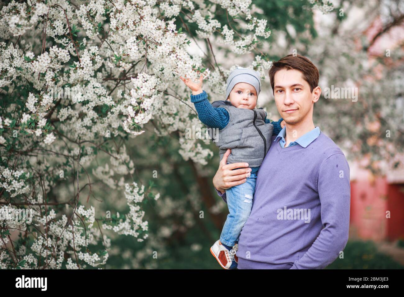 Happy father and son stand in the garden in spring against the ...