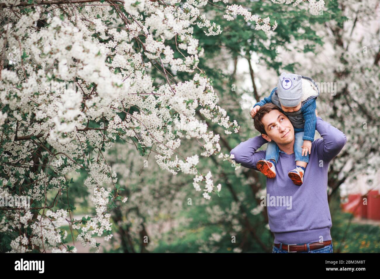 Happy father and son stand in the garden in spring against the ...