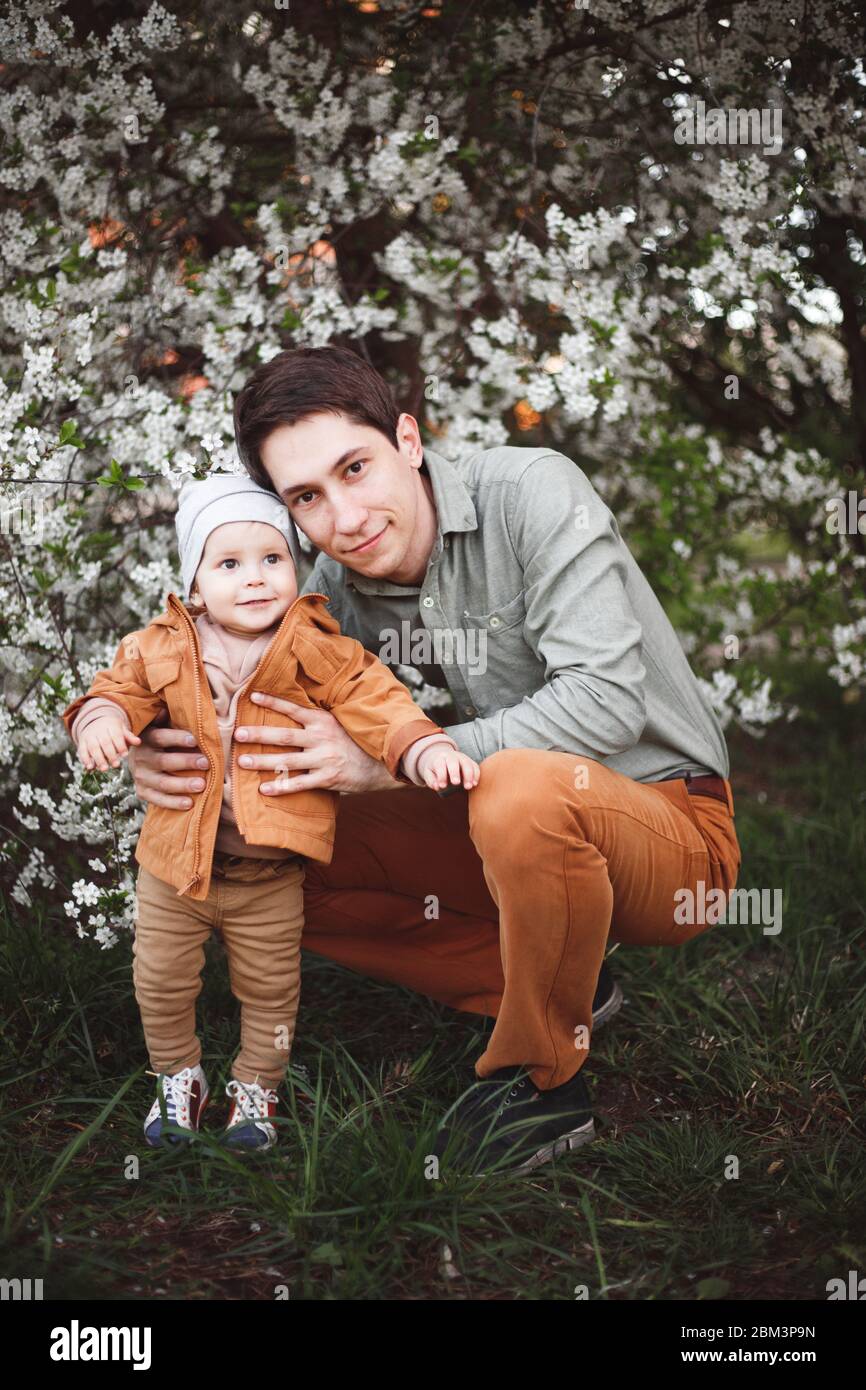 A father and a little boy are having fun near the cherry blossom trees ...