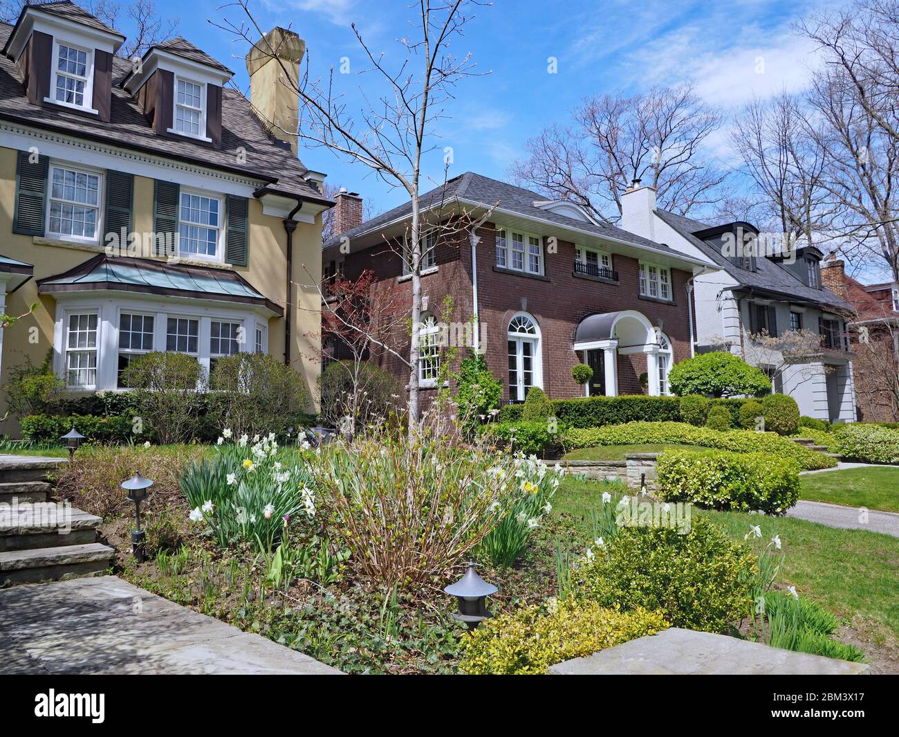 Street of large traditional detached homes with front yards with spring ...