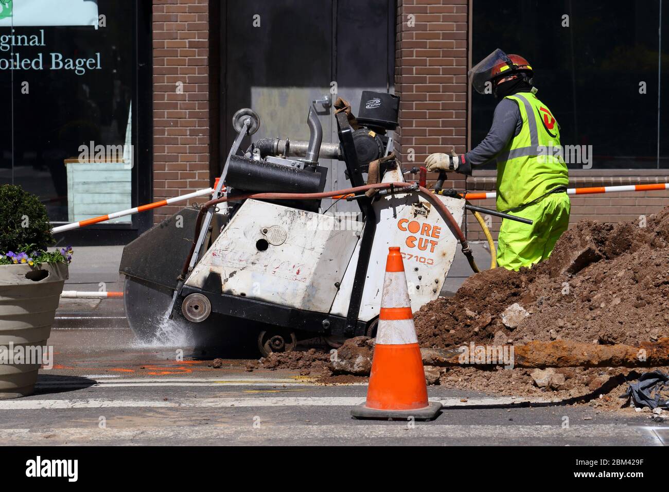 A construction worker wearing personal protective equipment operates a ...