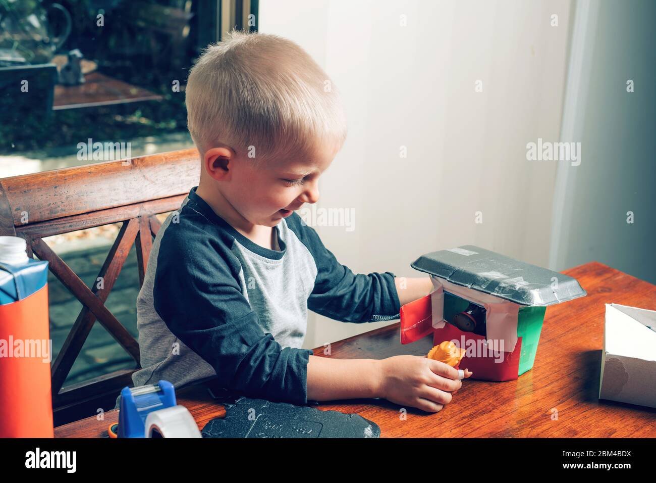 Little boy making crafts from different recycled materials and playing ...