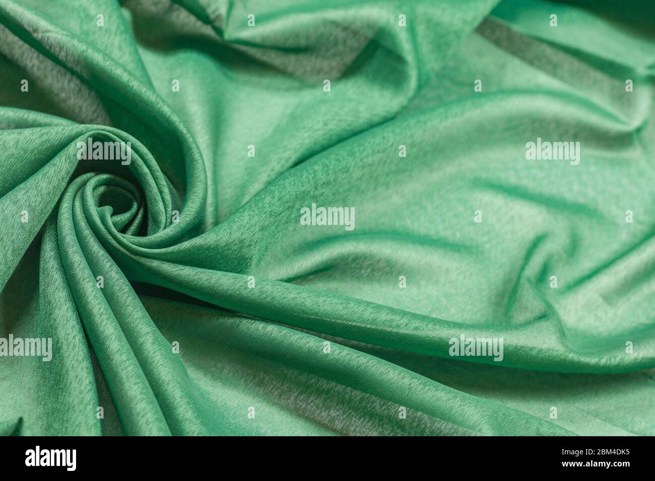 Creased green curved cloth material fragment with swirl as fabric ...