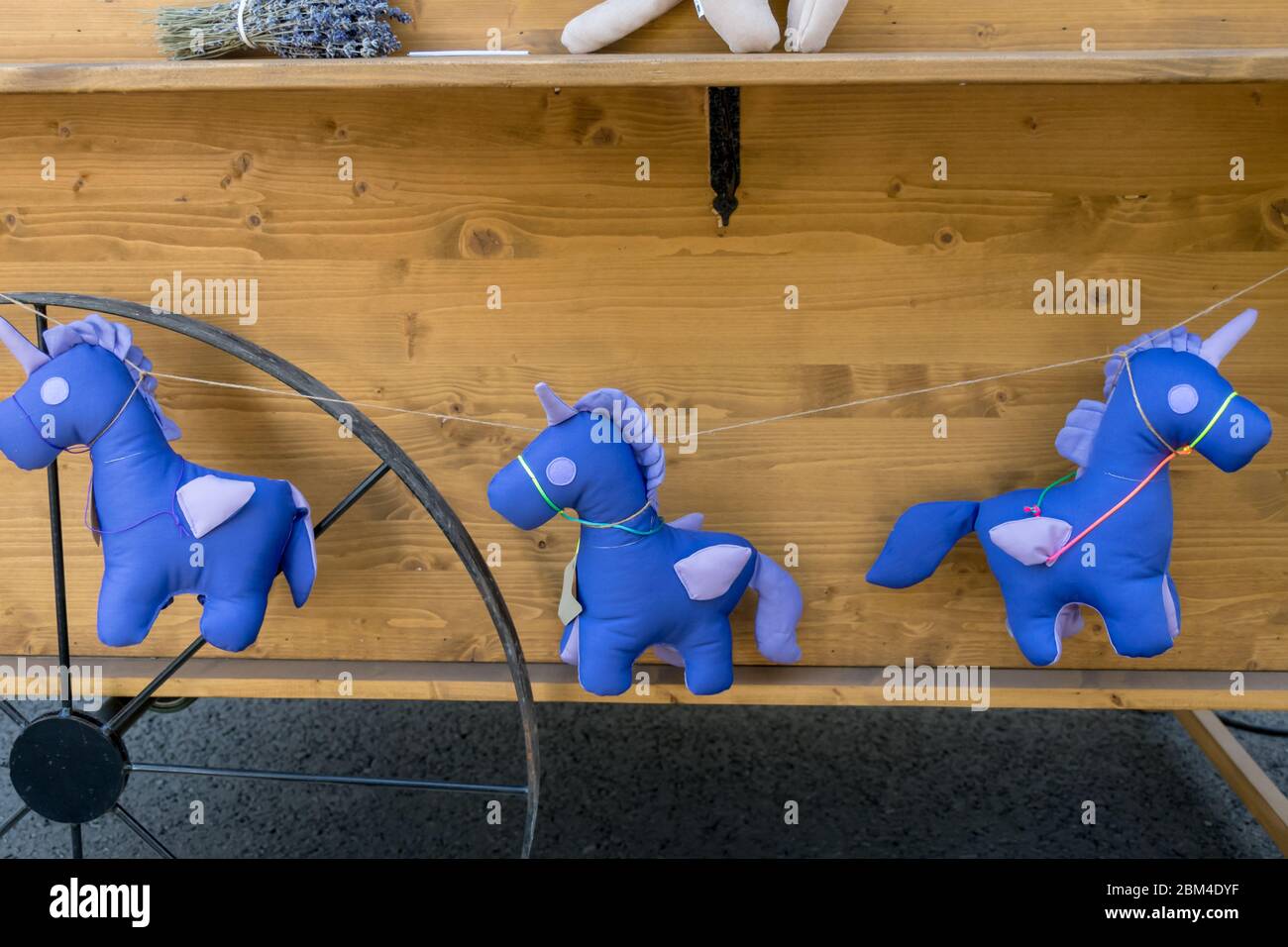 Purple unicorn toy hanging on a rope on a van during food festival ...