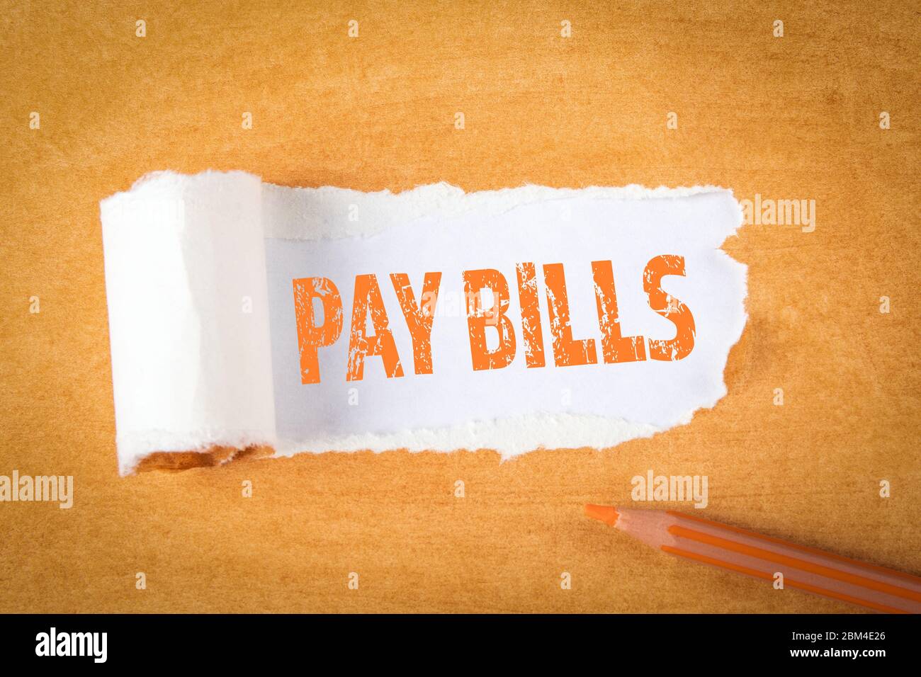 PAY BILLS concept. Text under torn paper. Orange pencil and office ...