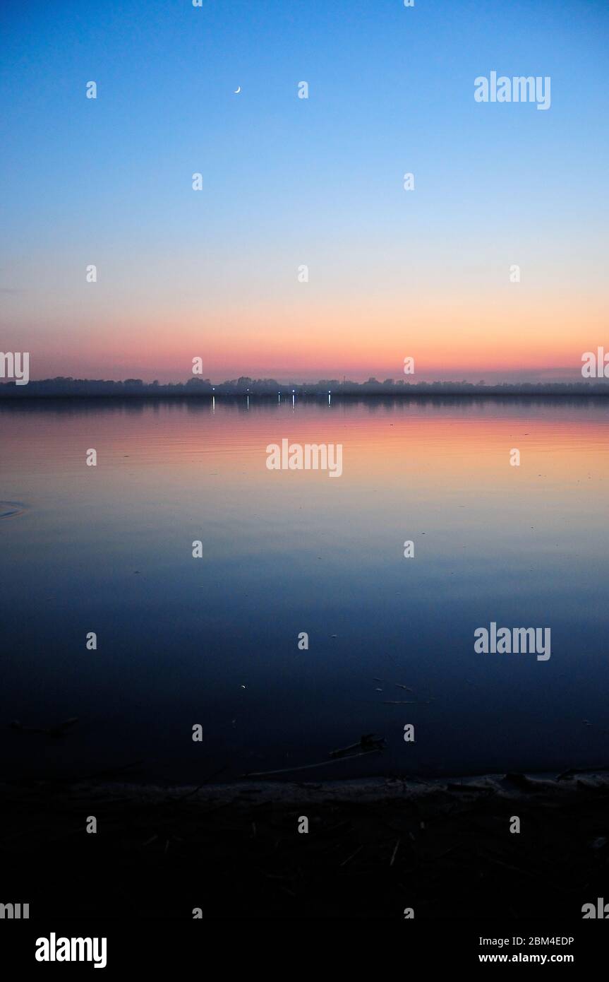 The shore of a wide river at sunset, the sun had already set, staining ...
