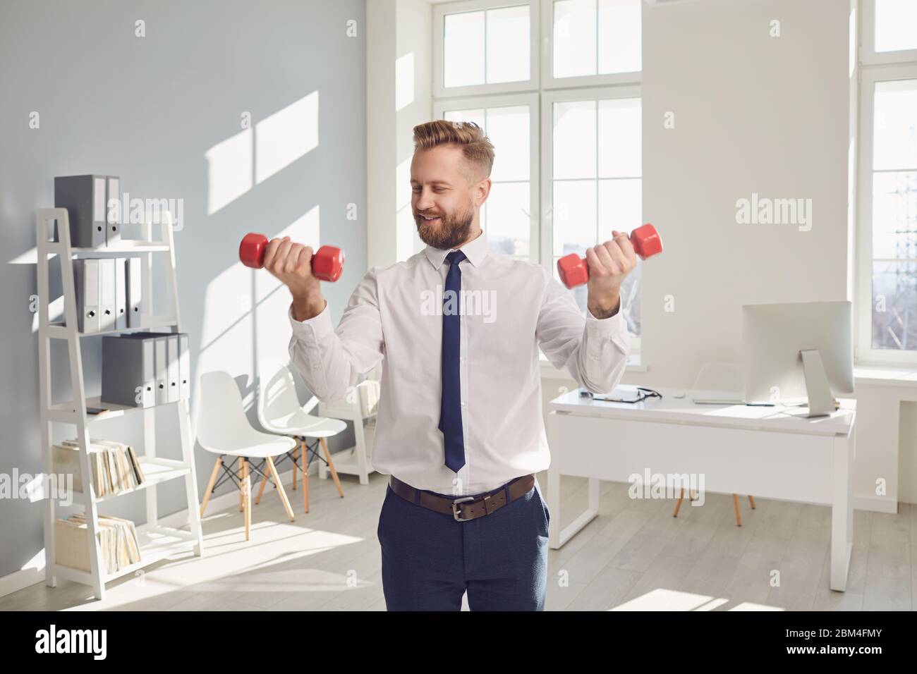 Happy successful businessman in a white shirt does exercises with ...