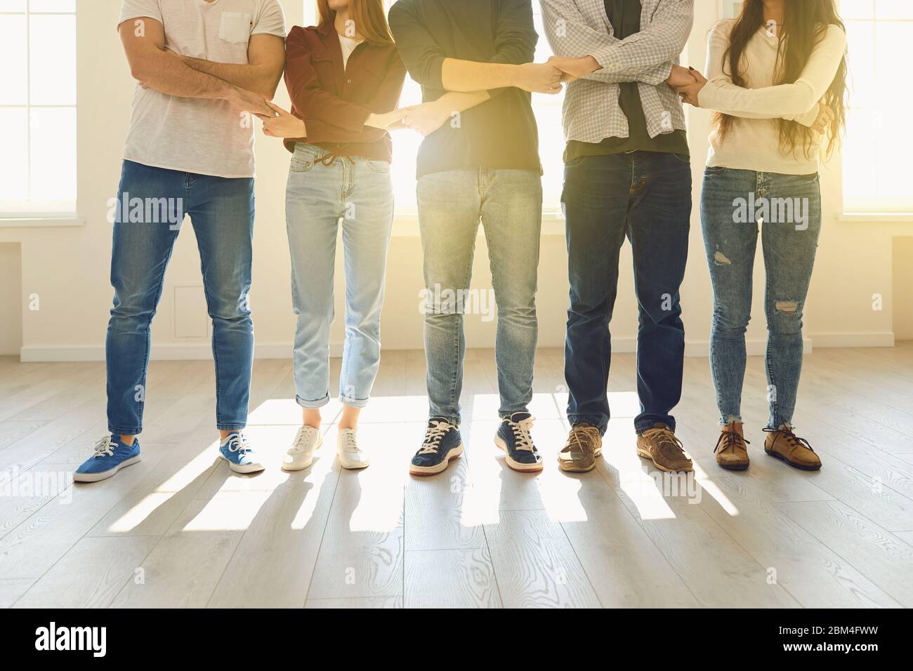 A group of people hold each other's hands while standing against the ...