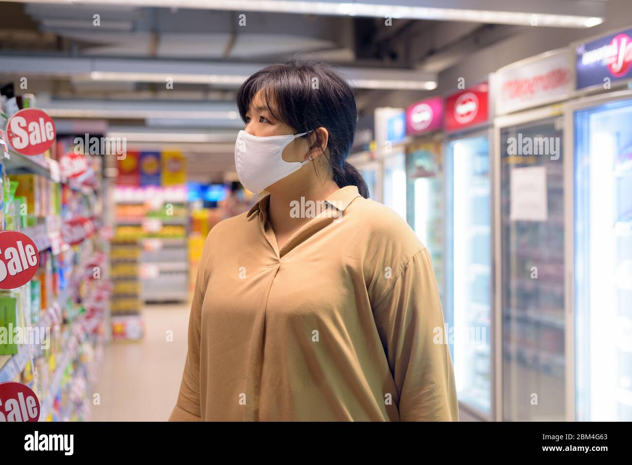 Overweight Asian woman with mask shopping inside supermarket Stock ...