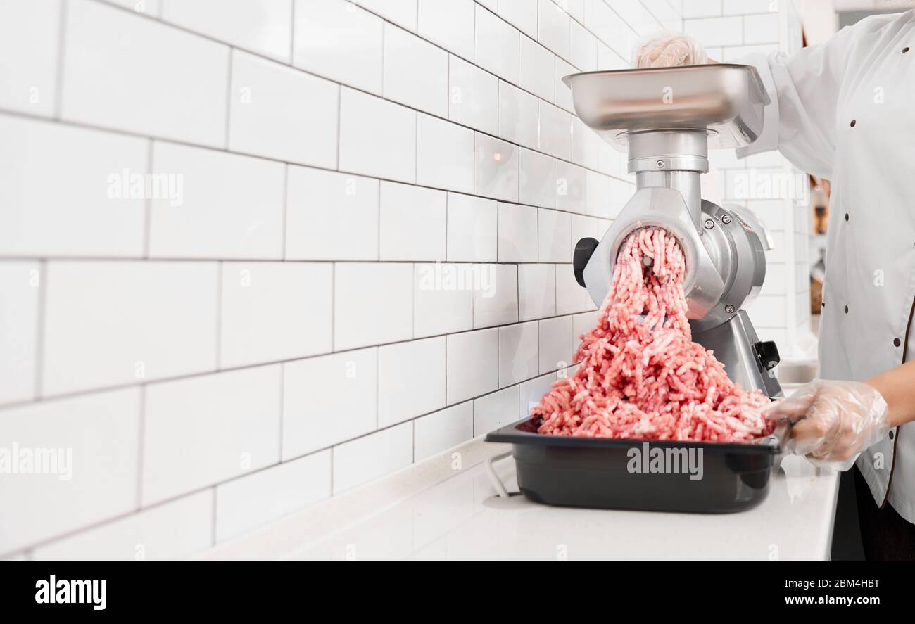 Crop of incognito woman with curly hair putting small pieces in meat ...