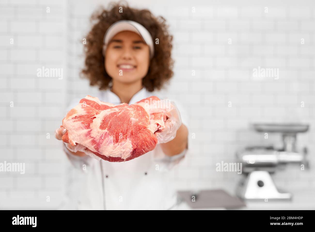 Selective focus of fresh red raw meat in hands of young smiling woman ...