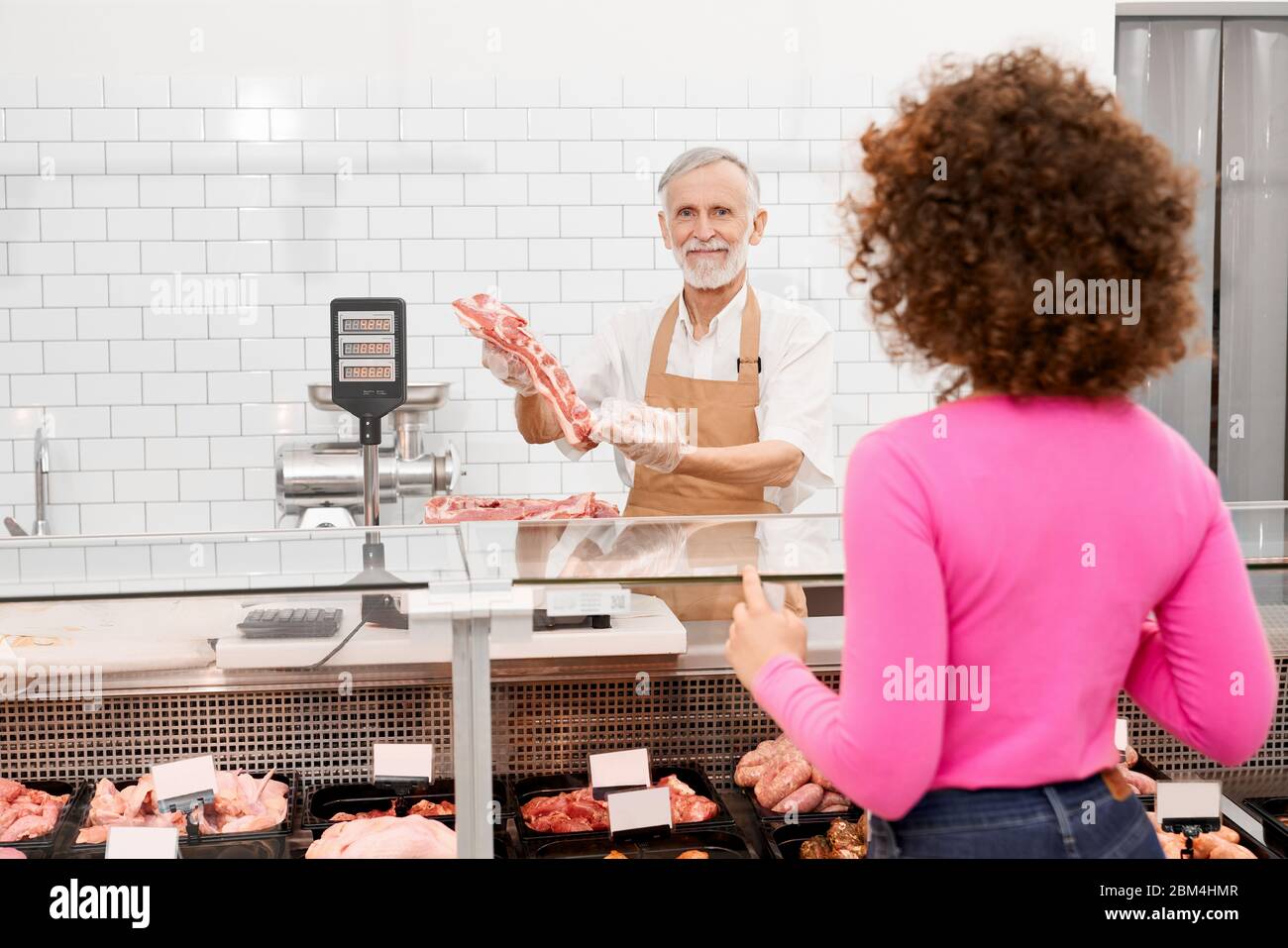 Selective focus of senior male butcher holding piece of fresh red raw ...