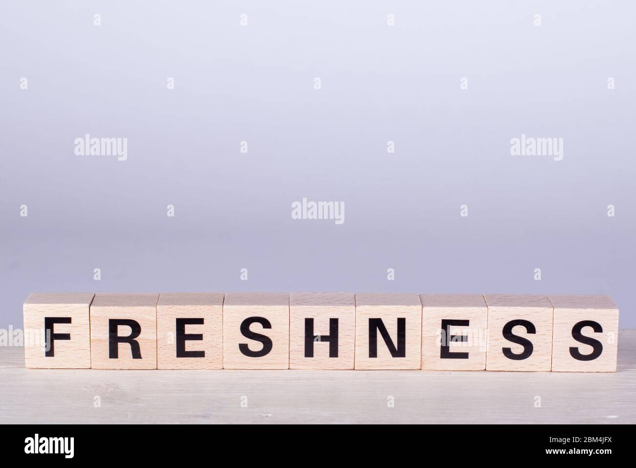wooden cubes building the word Freshness, white background and board ...