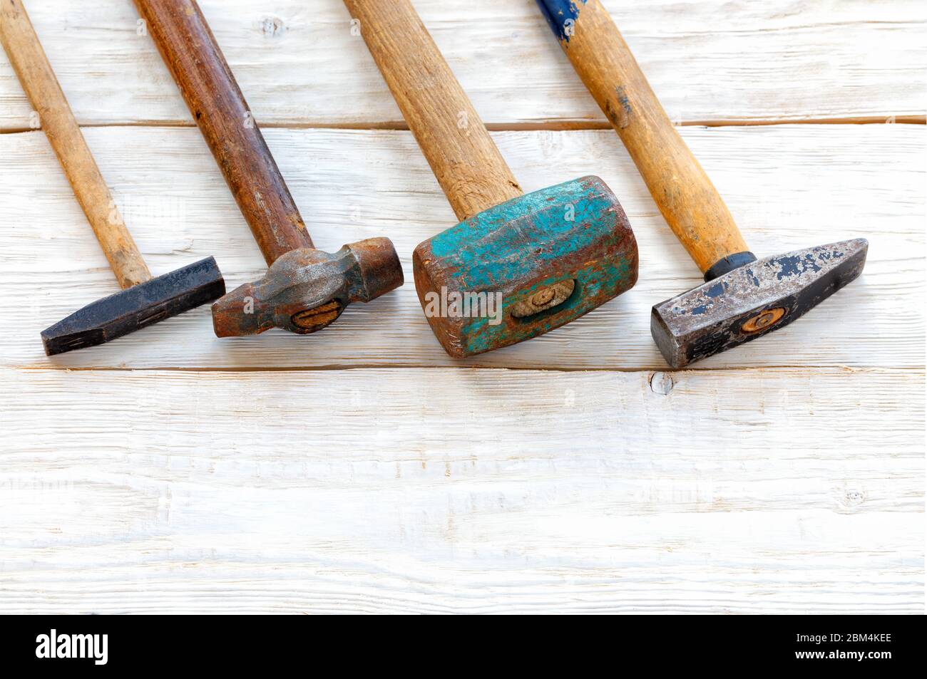 Old worn iron hammers with wooden handles are laid diagonally on a ...