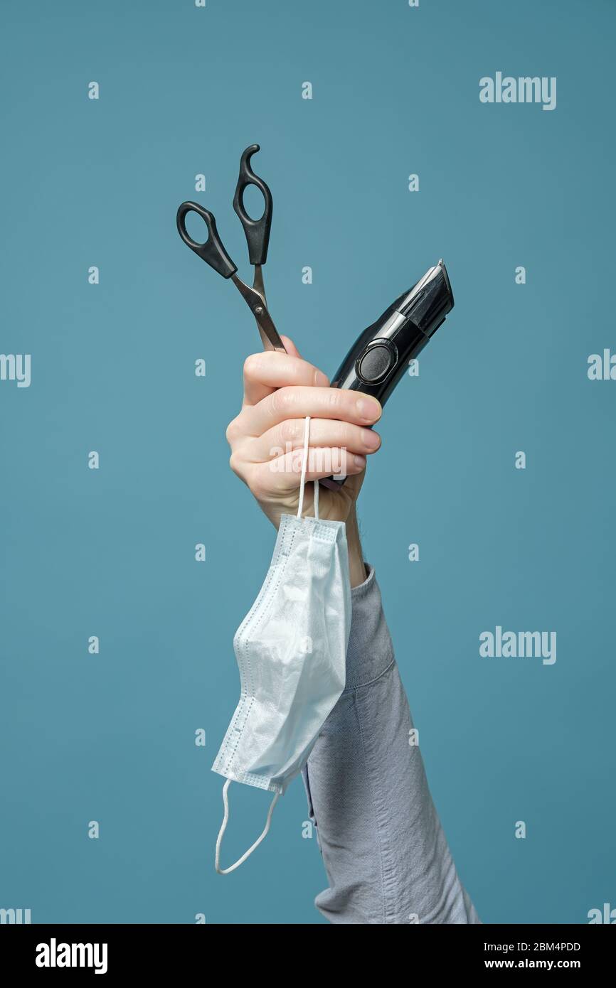 Male hand holds scissors, trimmer and medical mask. Concept of ...