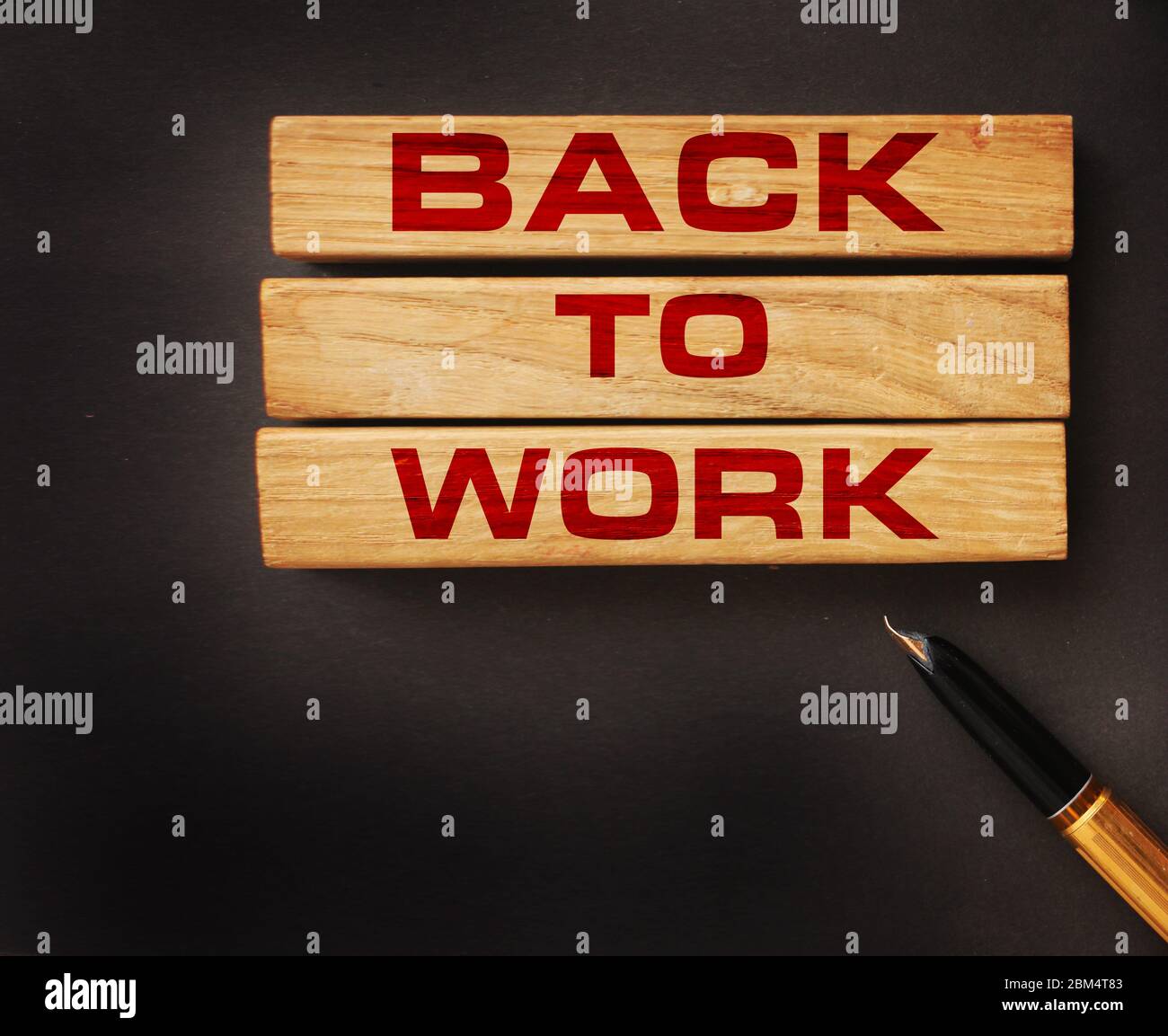 Words back to work written with wooden blocks on black background and ...
