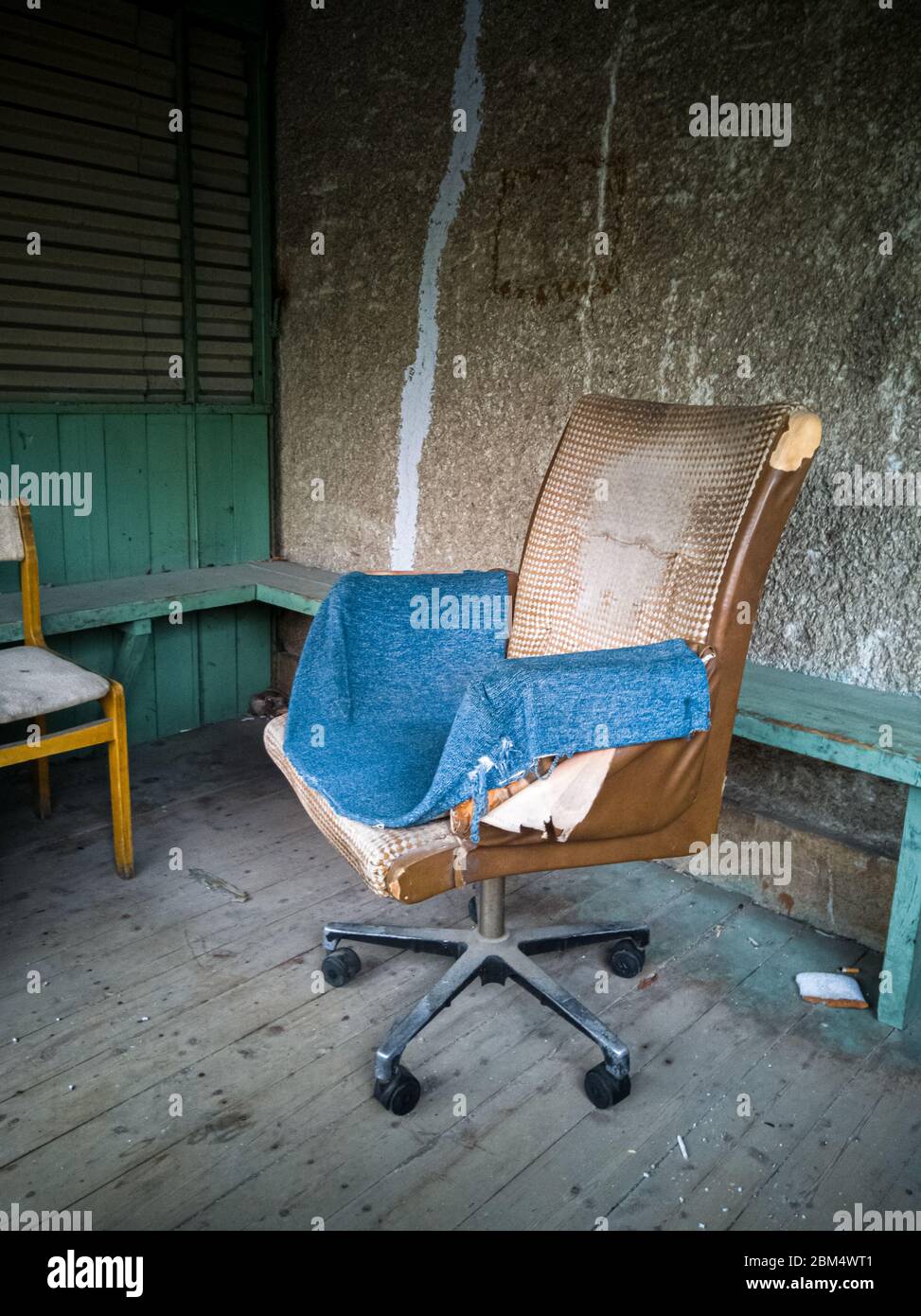 Old dirty vintage armchair covered with a blue rag against a rough ...