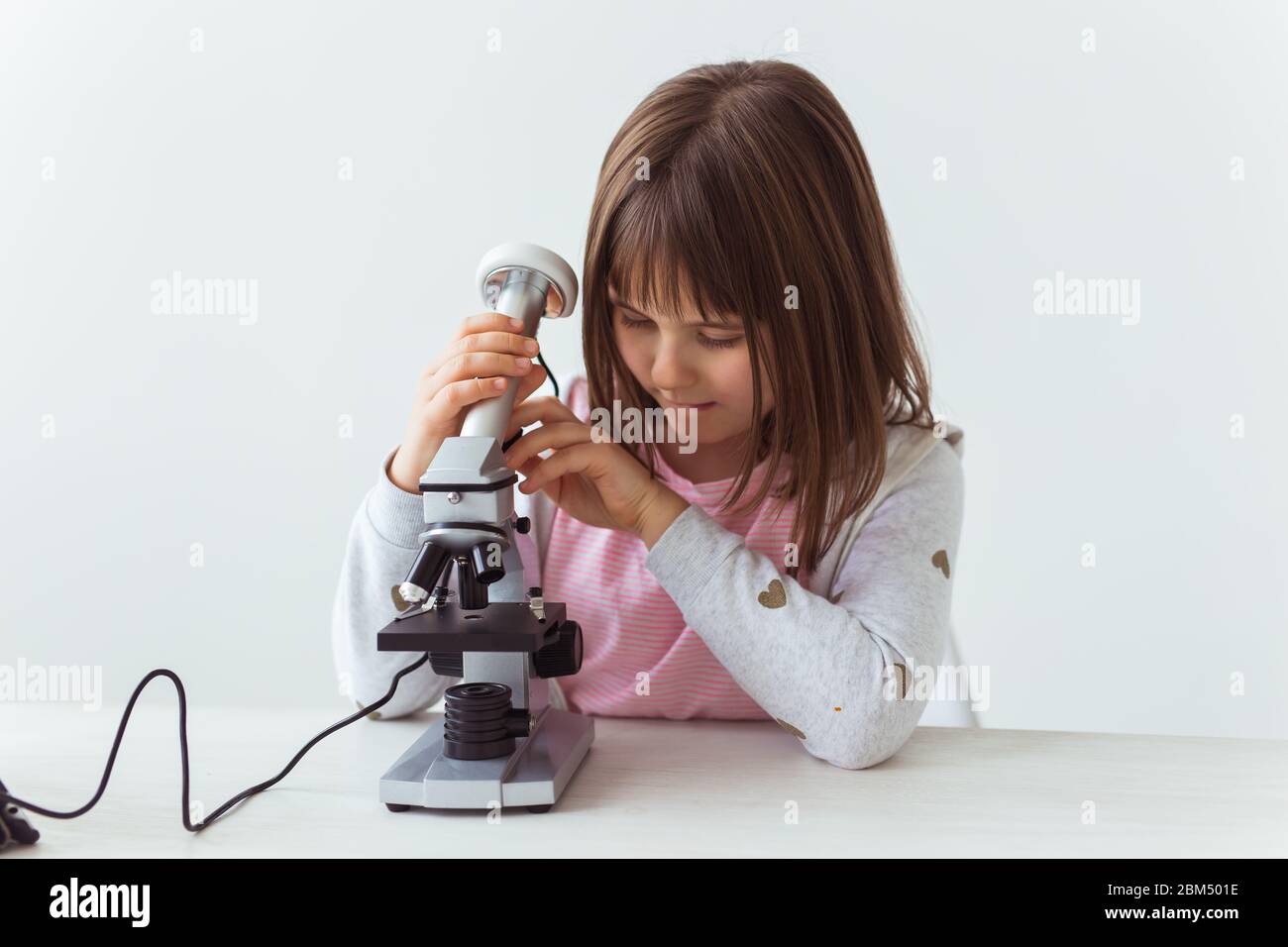Portrait of cute little child doing homework with a digital microscope ...