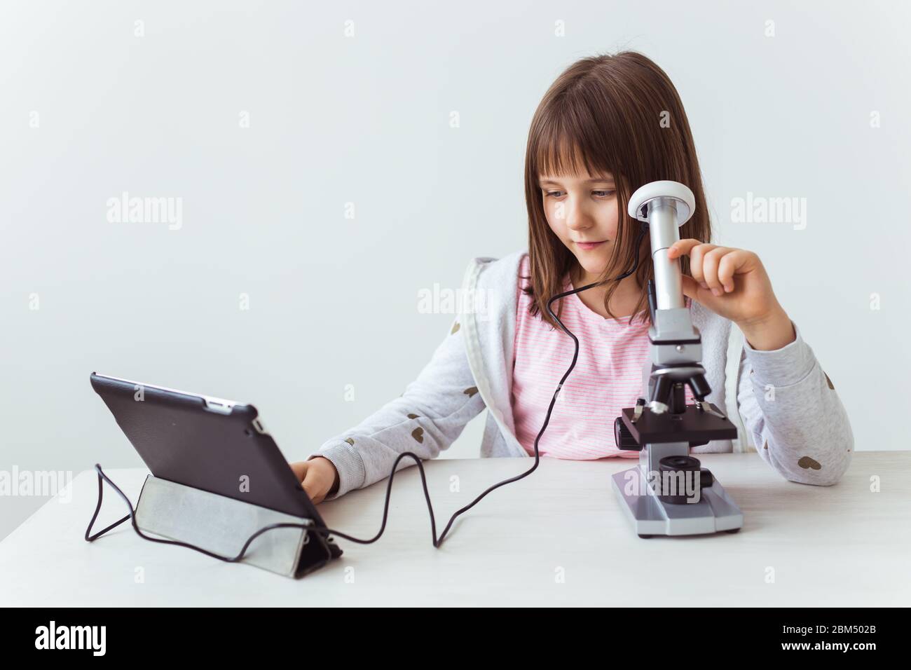 Portrait of cute little child doing homework with a digital microscope ...