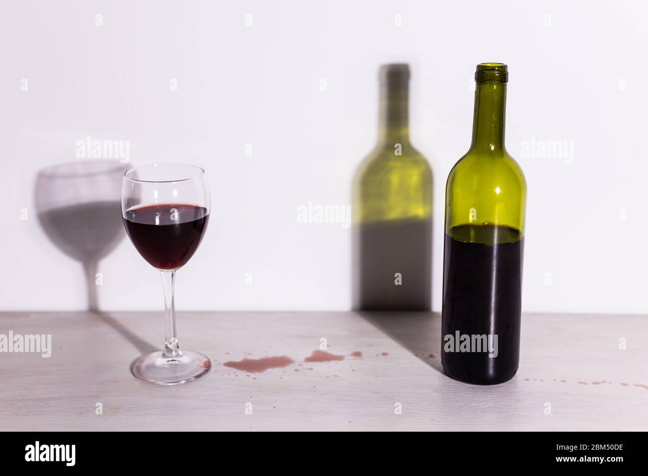 Bottle with wine and glass, red puddle of wine on the table. Cleaning ...