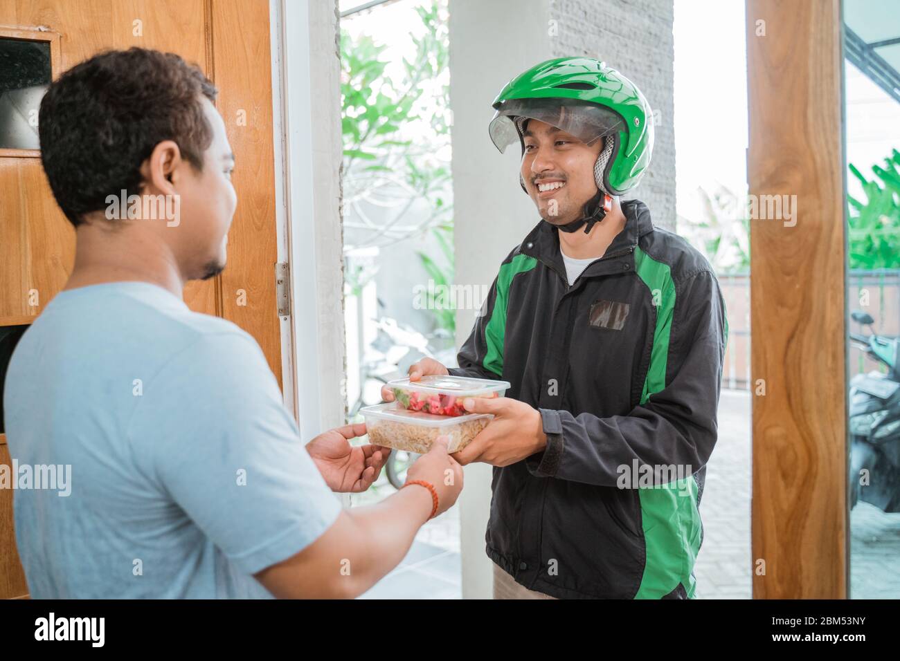 Delivery man delivering food to a man at home - online food shopping ...