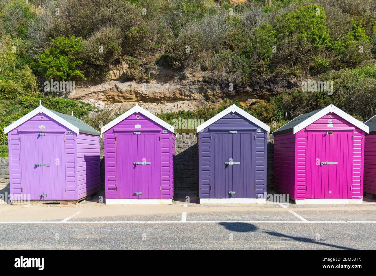 Colourful beach huts in shades of mauve purple pink with crumbling ...