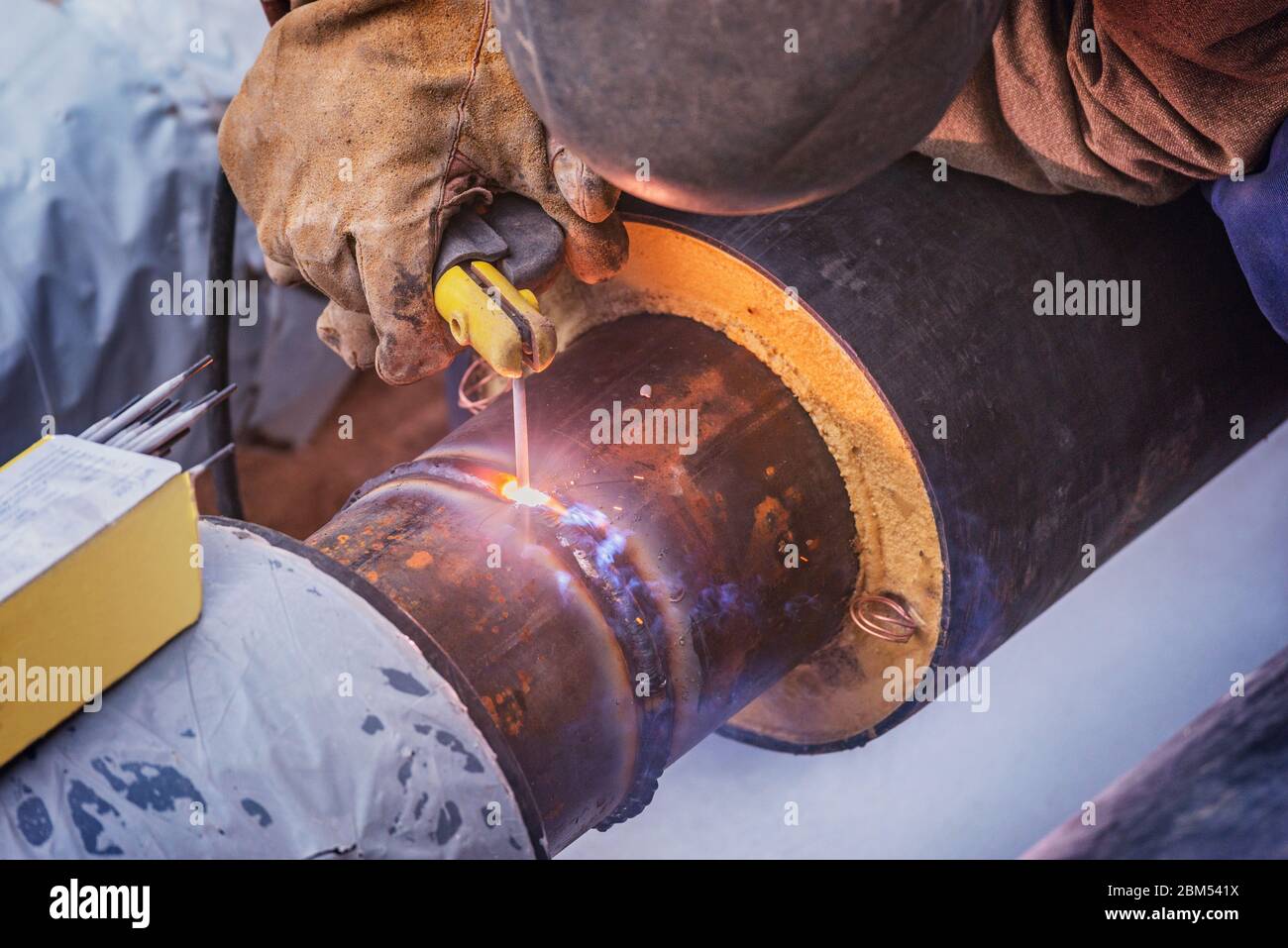 Welder worker welds new metal pipe Stock Photo - Alamy