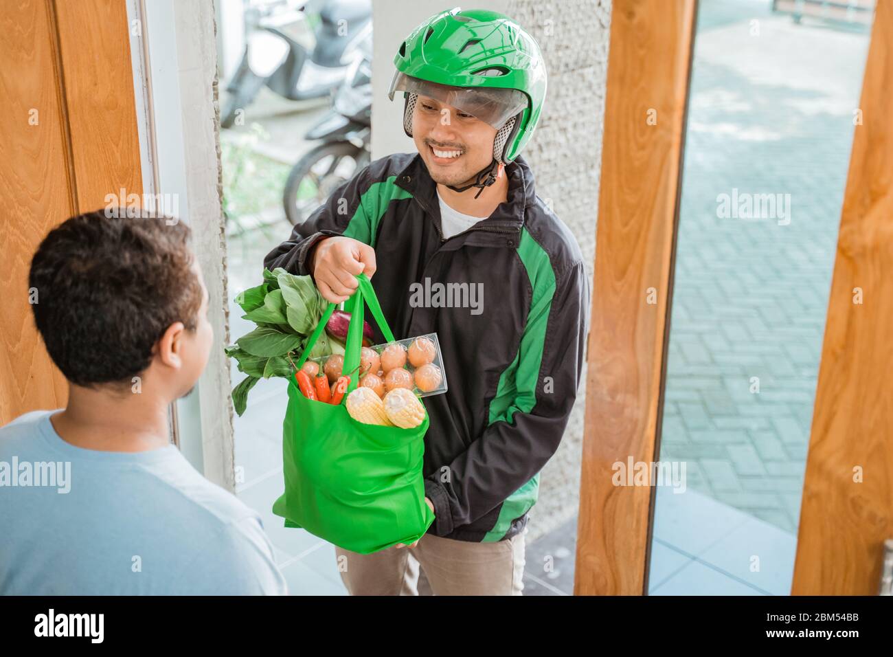 online grocery shopping. delivery man delivering food to a person at ...
