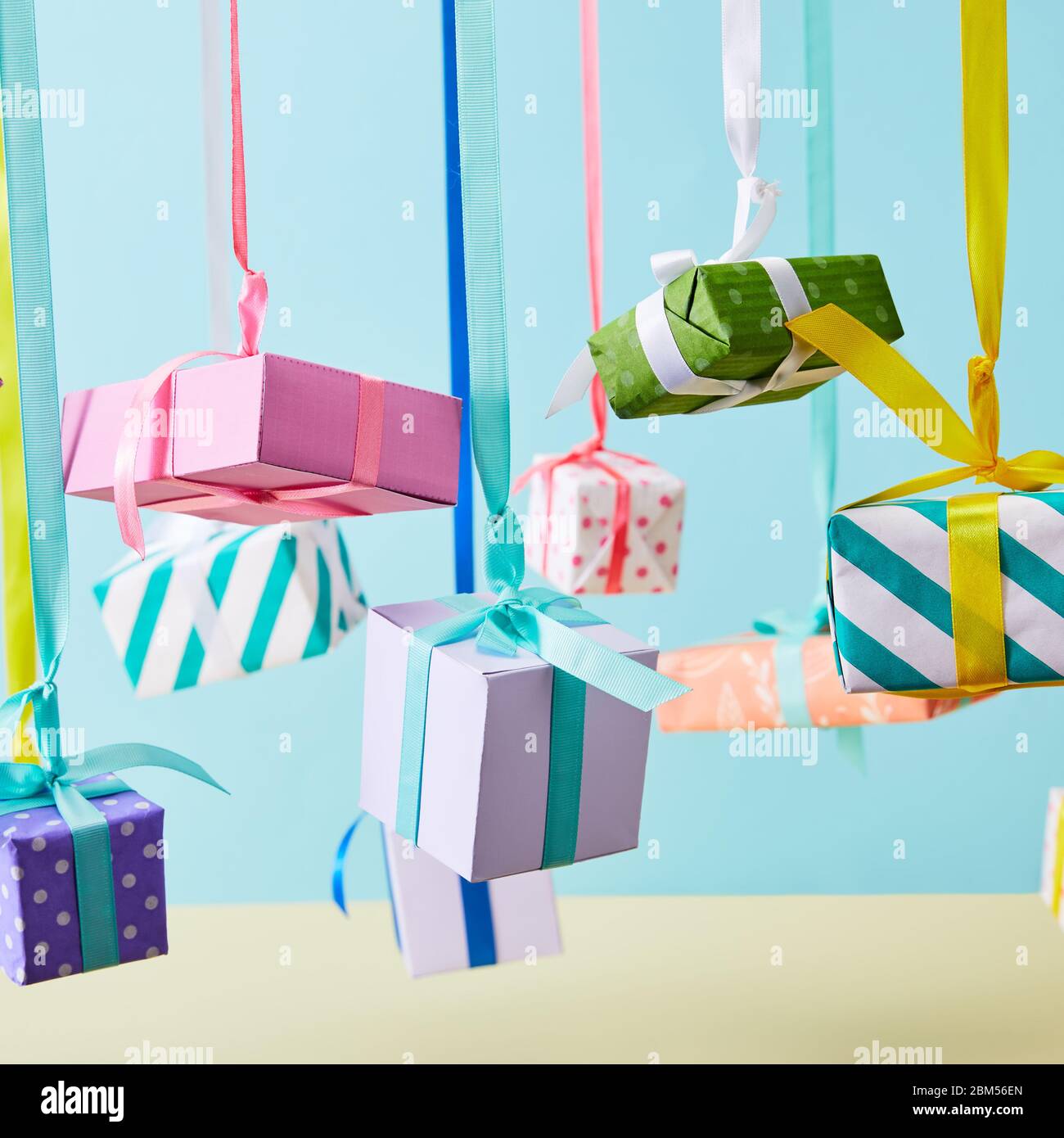 festive colorful gift boxes hanging on ribbons on blue background Stock ...