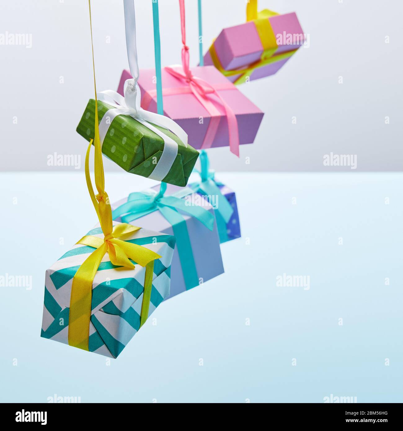 festive colorful gift boxes hanging on ribbons on blue background Stock ...