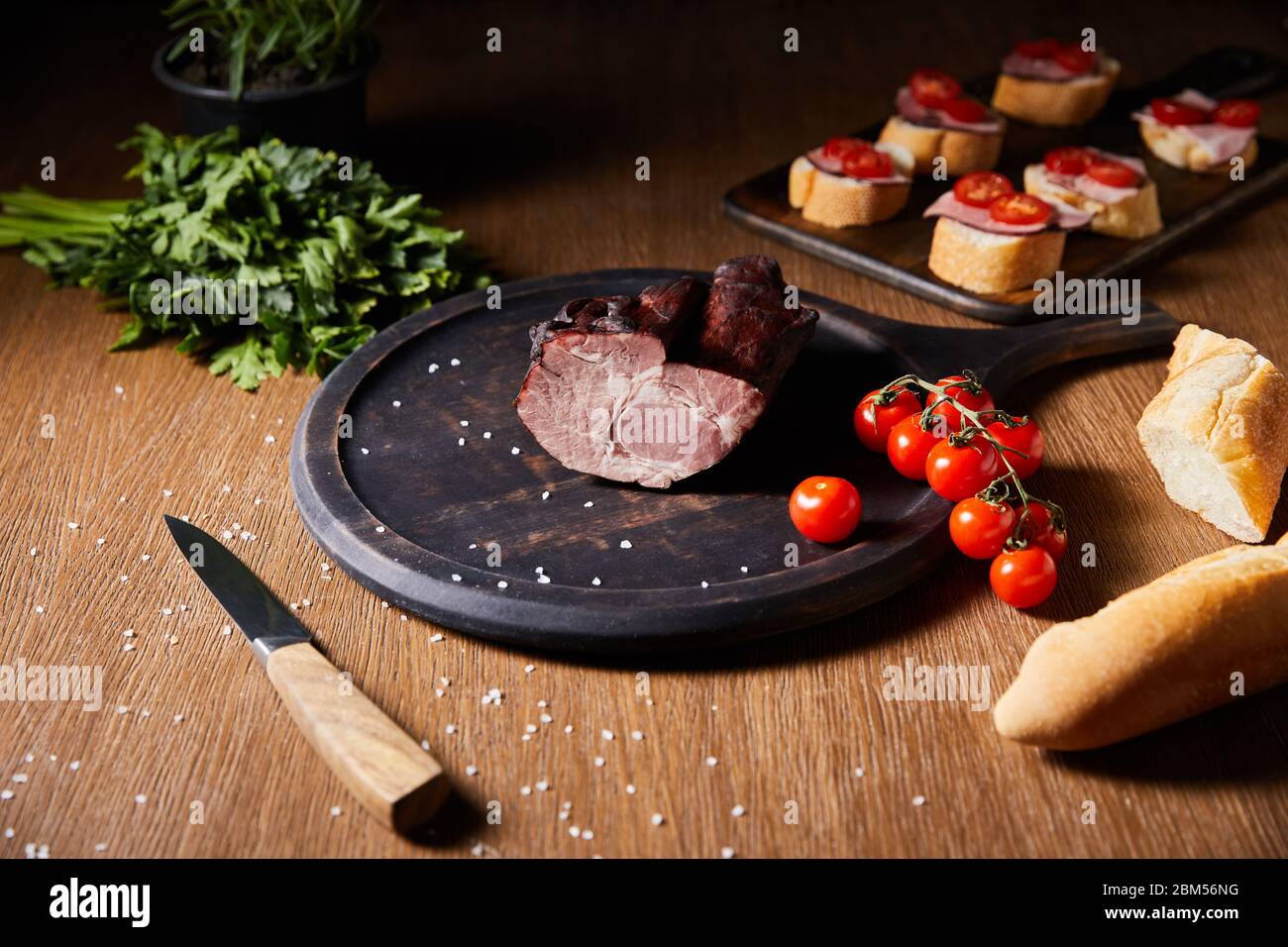selective focus of tasty ham on board near canape, parsley, cherry ...