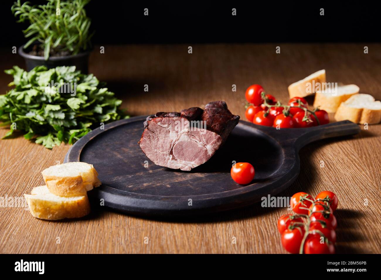 selective focus of tasty ham on board near parsley, cherry tomatoes and ...