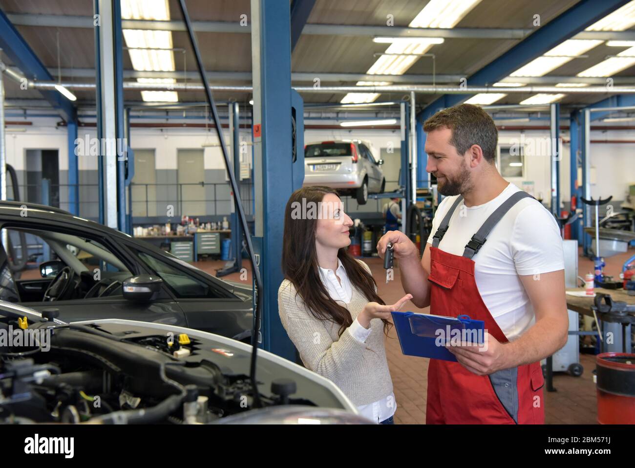 Customer service: car mechanic and customer handing over the keys after ...