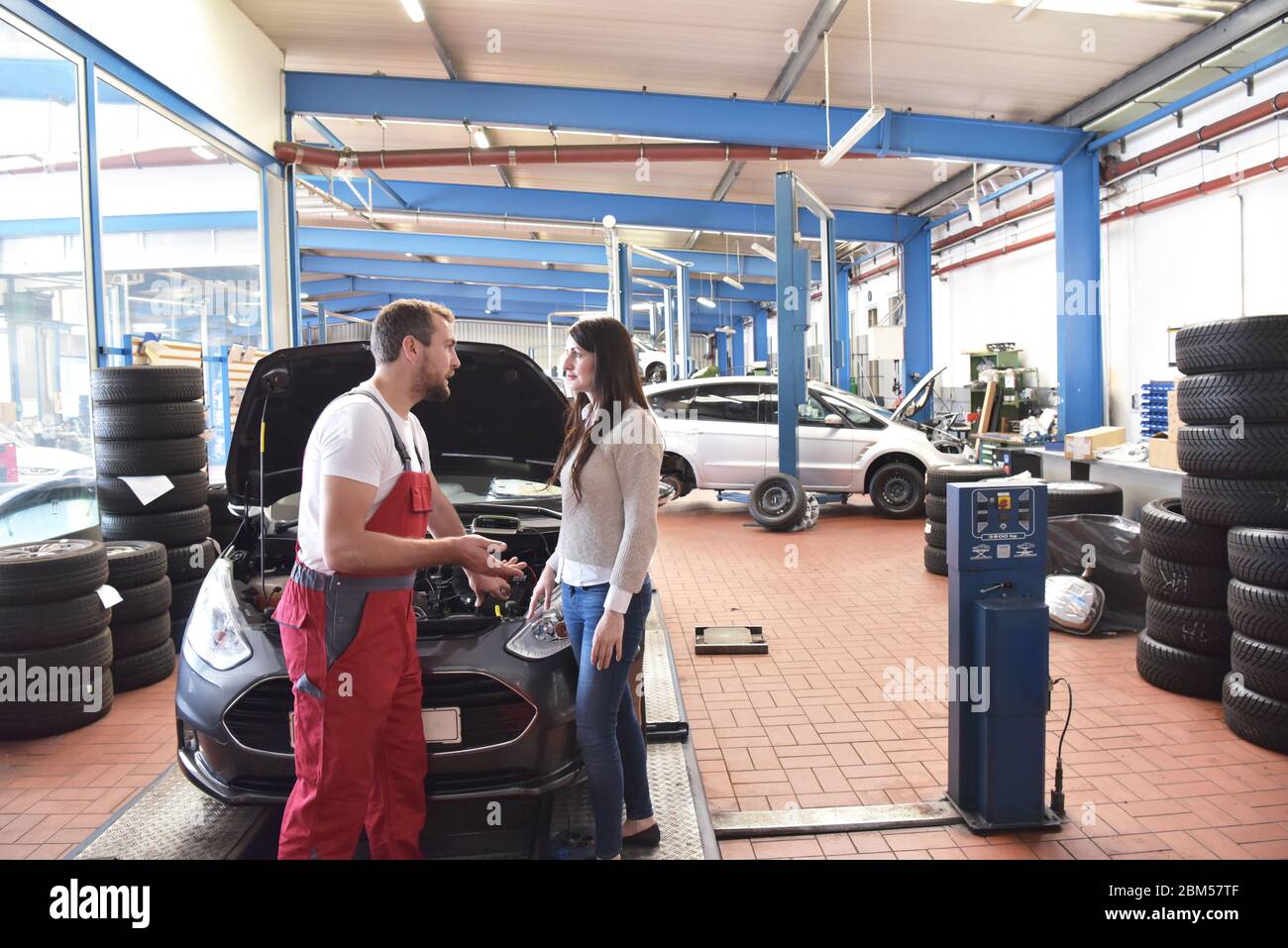 Customer service: car mechanic and customer discuss the repair of a ...