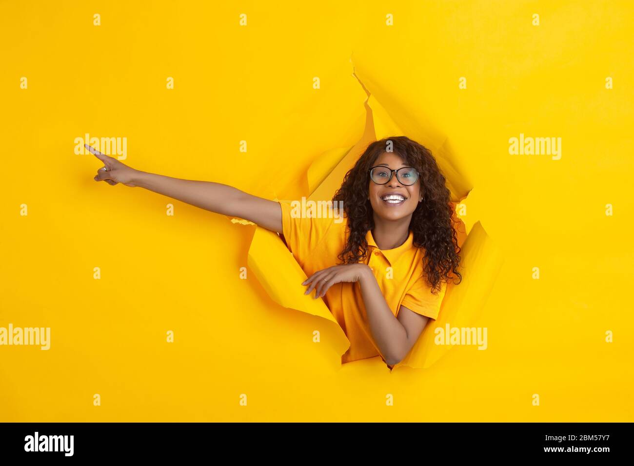 Crazy happy pointing. Cheerful african-american young woman in torn ...
