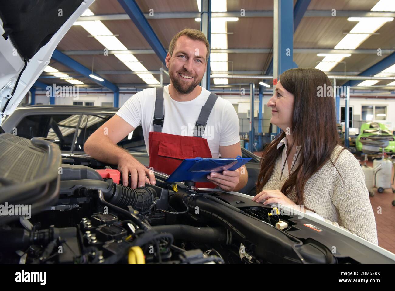 mechanic and customer talking in a workshop to repair a vehicle Stock ...