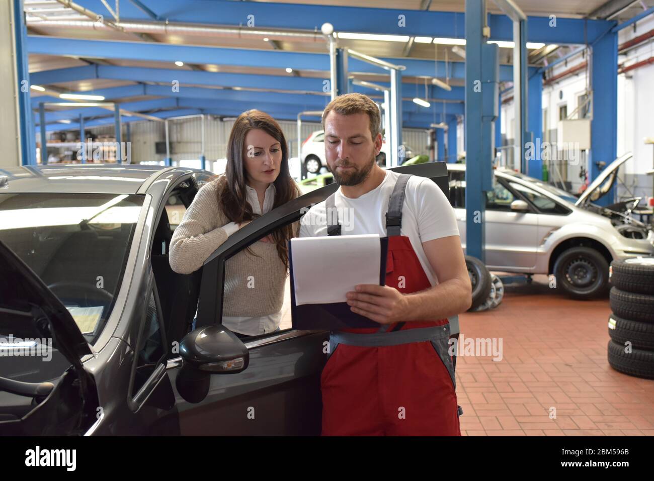 Customer service: car mechanic and customer discuss the repair of a ...