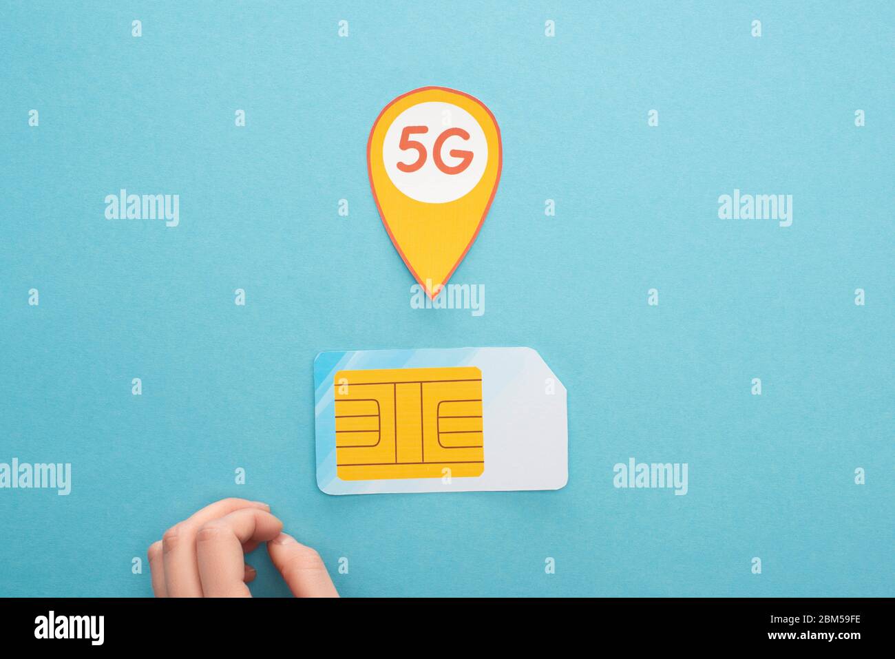 top view of female hand, sim card and 5g lettering on blue background ...