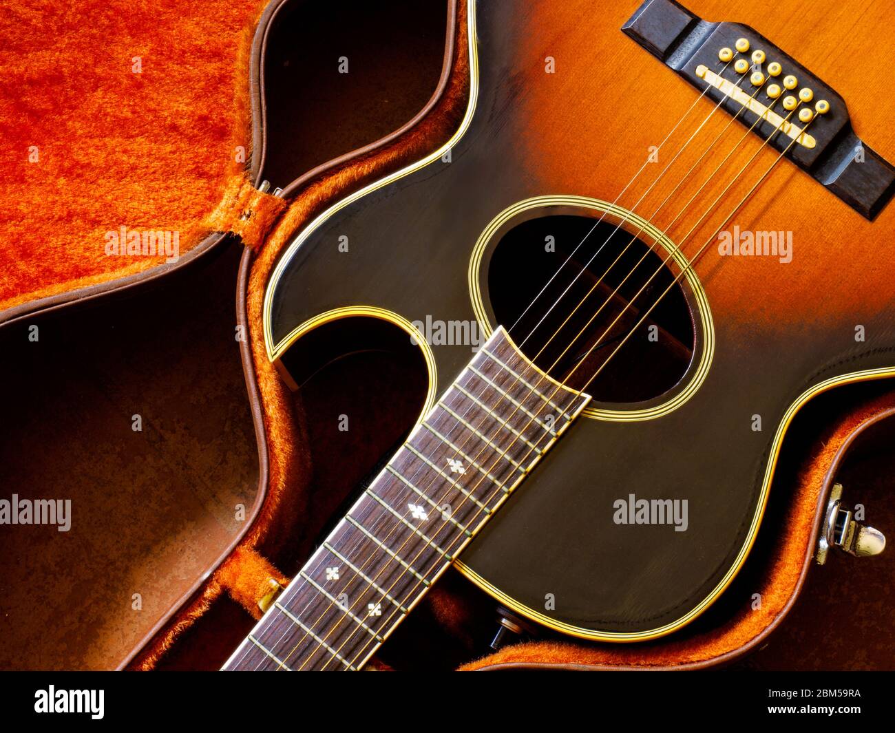 A closeup of an acoustic guitar in an open hard case. Taken from above ...