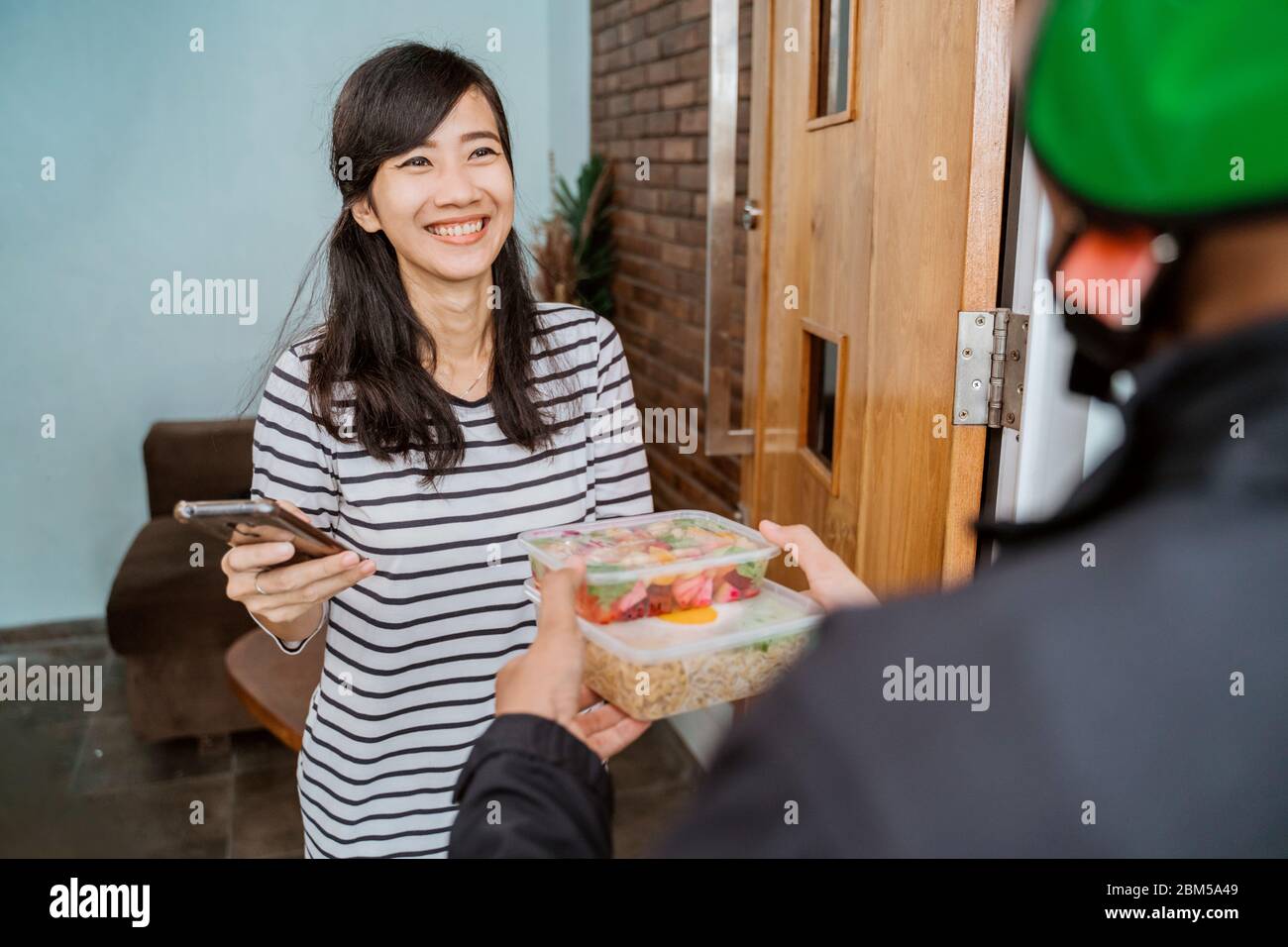 Delivery man delivering food to a woman at home. online food shopping ...
