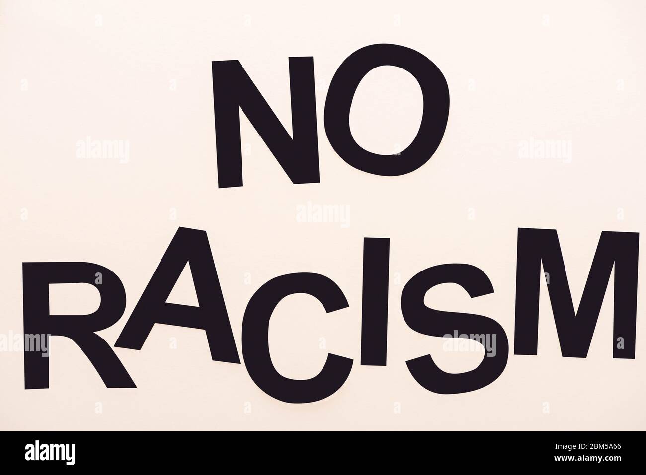 top view of black no racism lettering isolated on beige Stock Photo - Alamy
