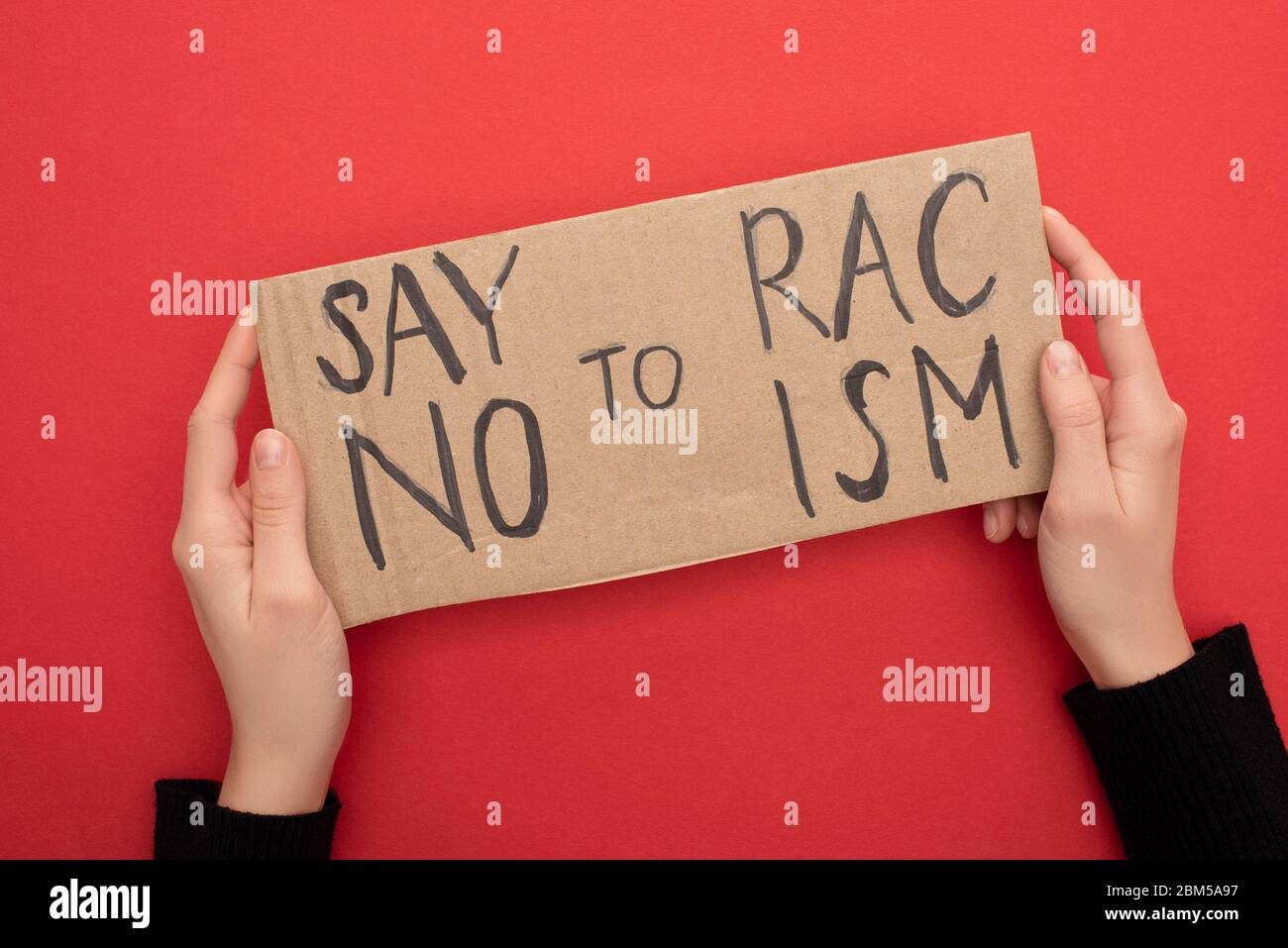 cropped view of woman holding carton placard with say no to racism ...