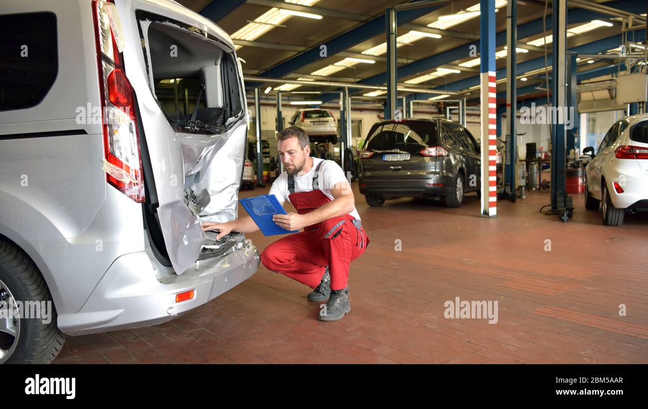 Car mechanic examines accident vehicle in a workshop for repair Stock ...
