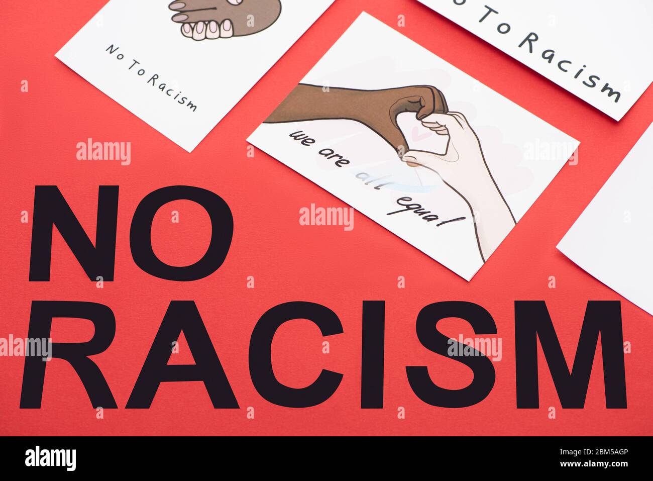top view of black no racism lettering among pictures with multiethnic ...