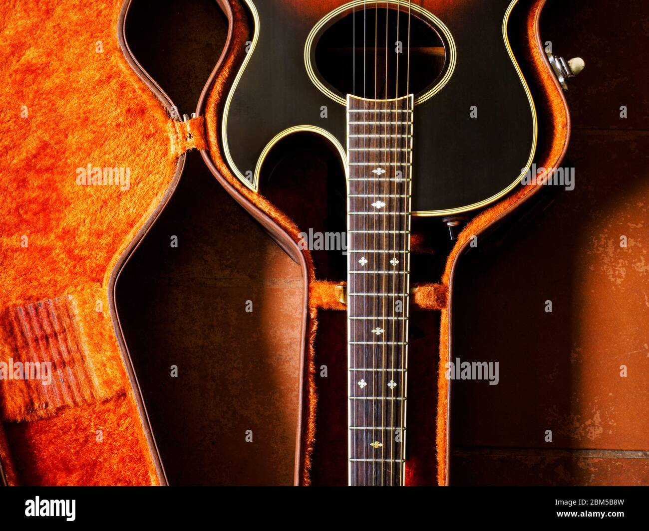 A closeup of an acoustic guitar in an open hard case. Taken from above ...