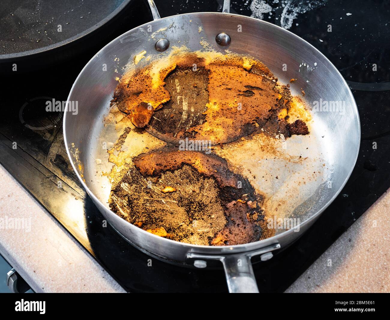 steel stewpan with crust of food burned while cooking on electric stove ...