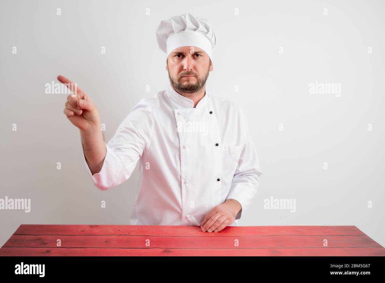 Young male chef in white uniform showing no with her finger posing on a ...