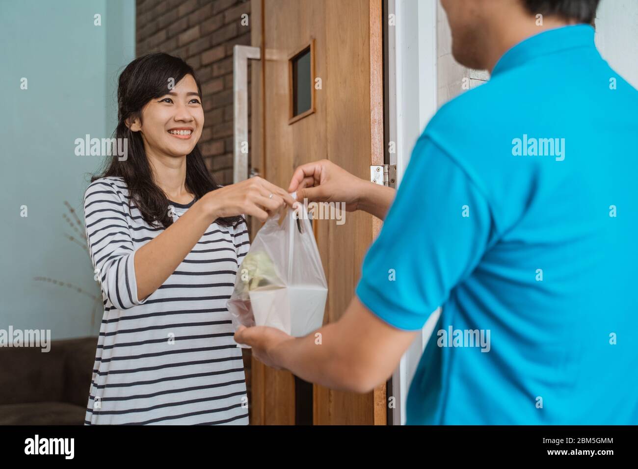 Delivery man delivering food to a woman at home. online food shopping ...